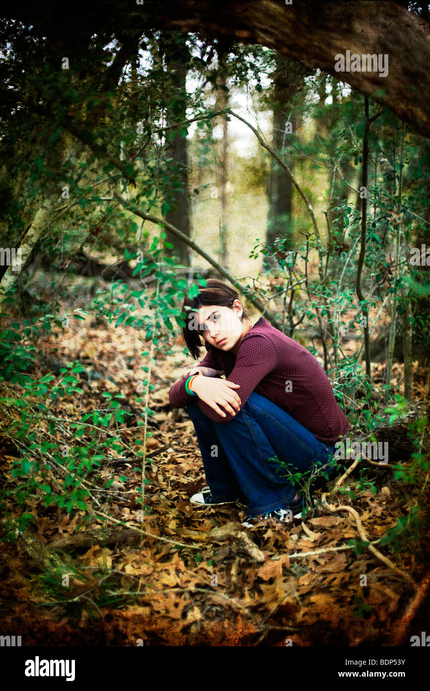 A young girl sitting alone in the woods looking at the camera Stock ...