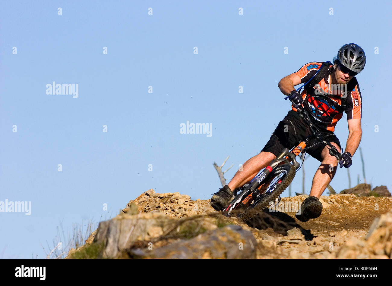 A mountain biker turns at speed on a banked rocky corner at Cwmcarn in ...