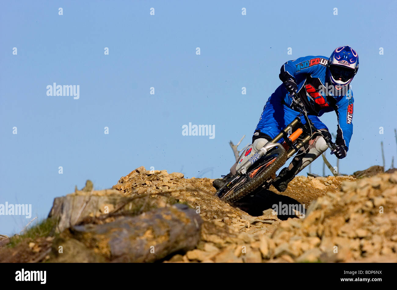 A downhill mountain biker turns a banked rocky corner at speed at ...