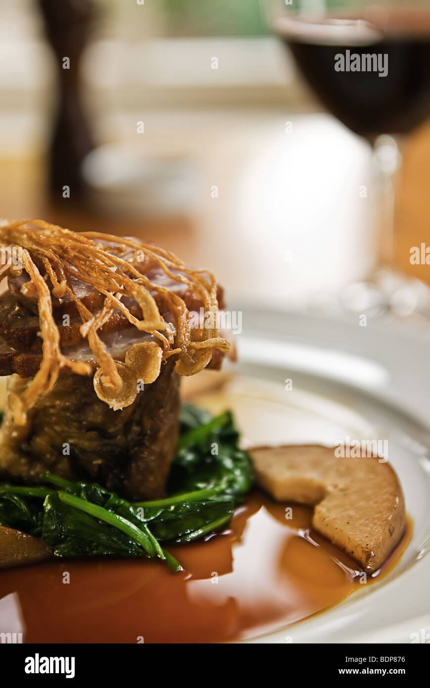 Crispy duck on a bed of spinach served with red wine in a restaurant ...