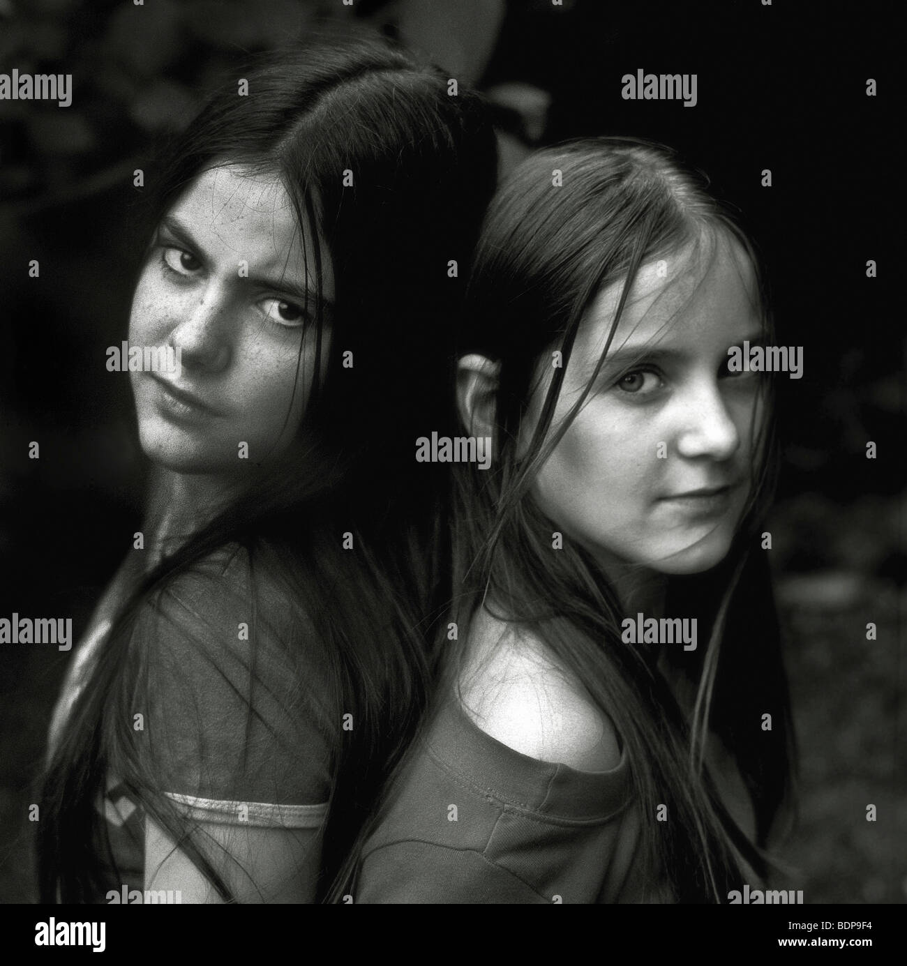 Two young women standing back to back Stock Photo - Alamy