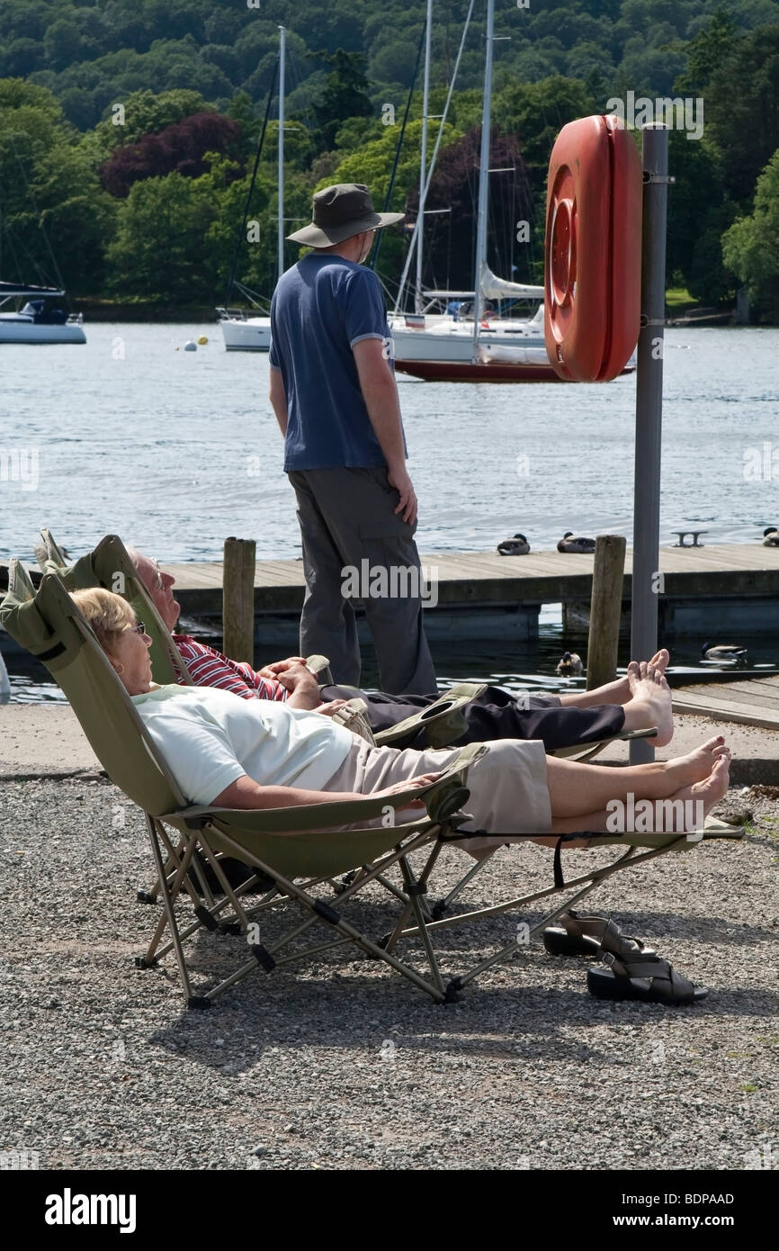 Two people sunbathing in deckchairs Stock Photo - Alamy