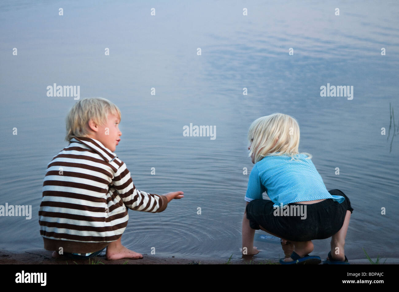 Two children talking at the waters edge Sweden Stock Photo - Alamy