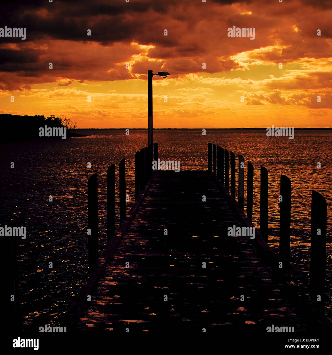 A wooden jetty leading to the sea at sunset Stock Photo - Alamy