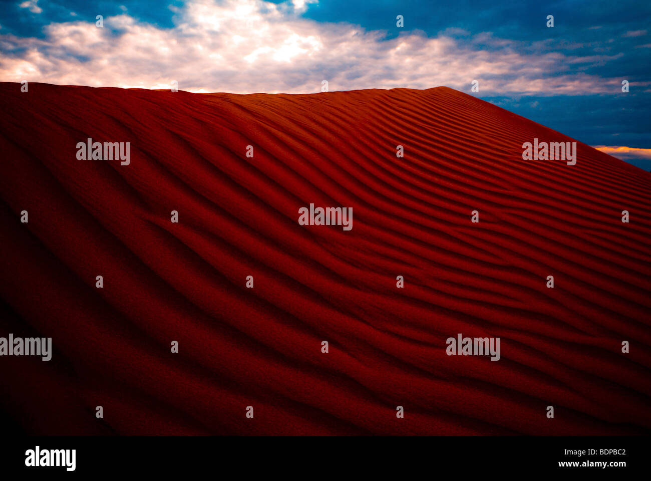 Red sand dunes under a sky with clouds Stock Photo - Alamy