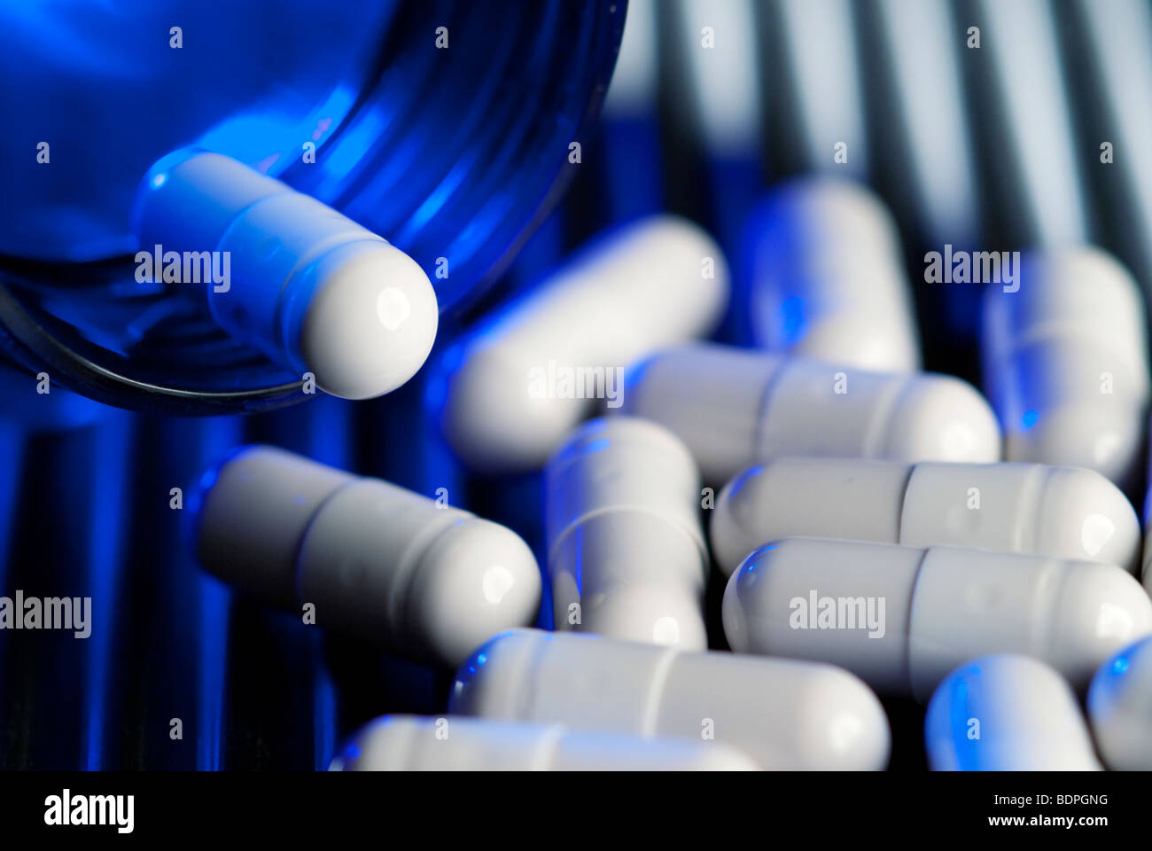 White capsules pouring out of blue plastic prescription bottle Stock ...