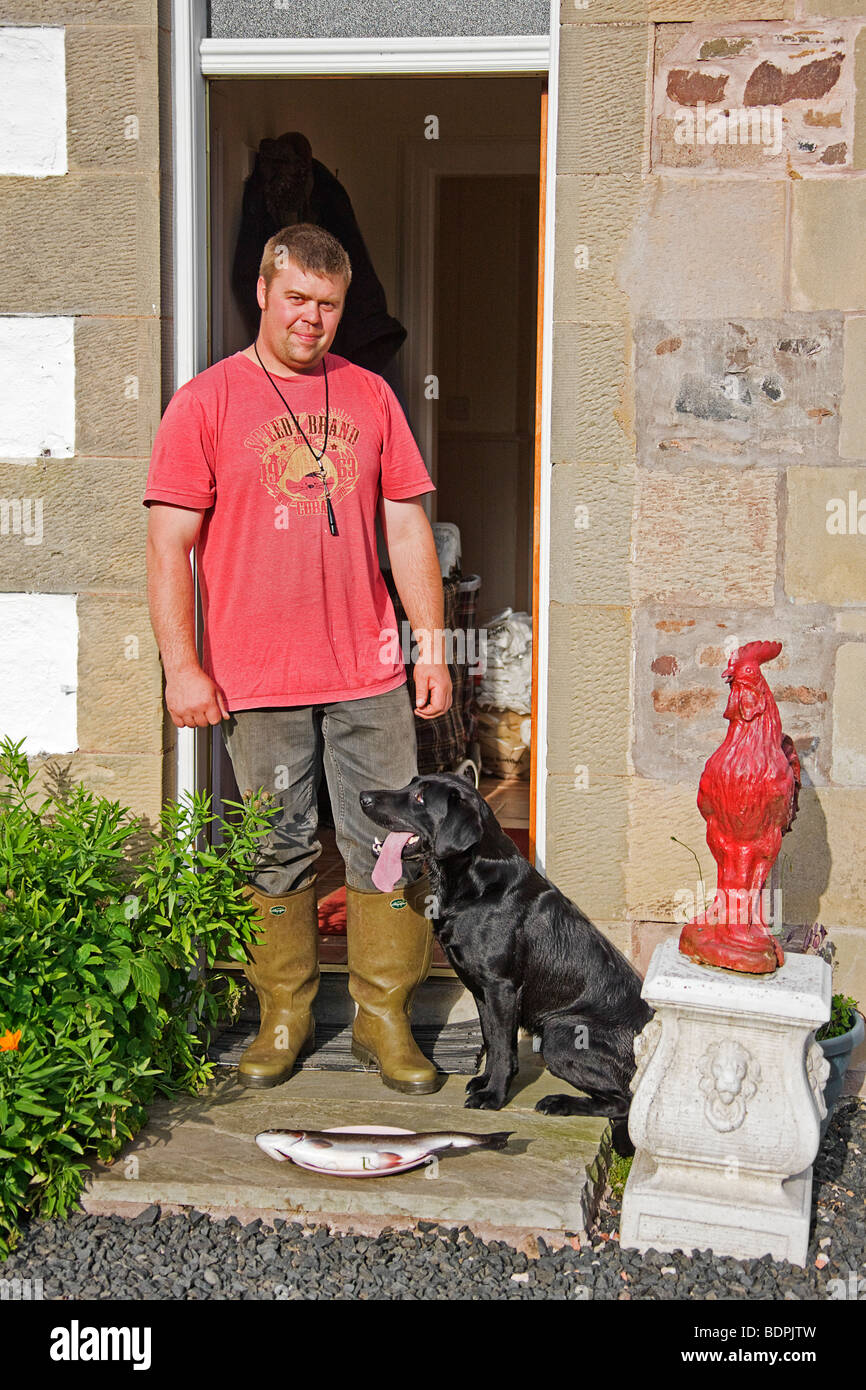 Man with dog in doorway showing his catch a rainbow trout Stock Photo ...