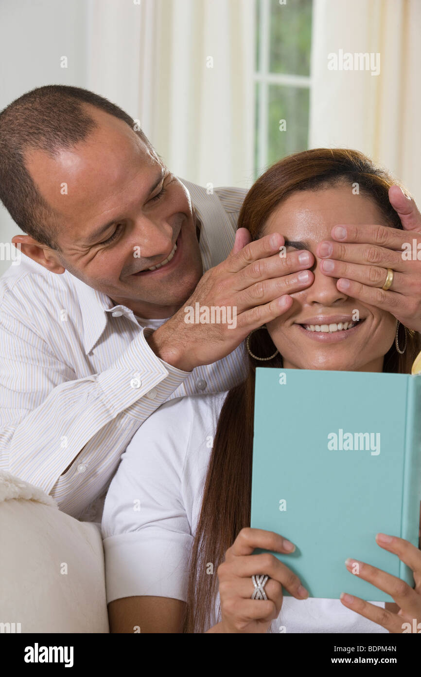 Hispanic man covering a woman's eyes from behind Stock Photo - Alamy