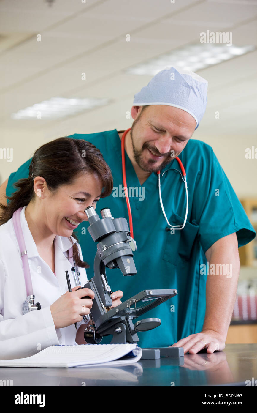 Female lab technician analyzing a sample through a microscope Stock ...