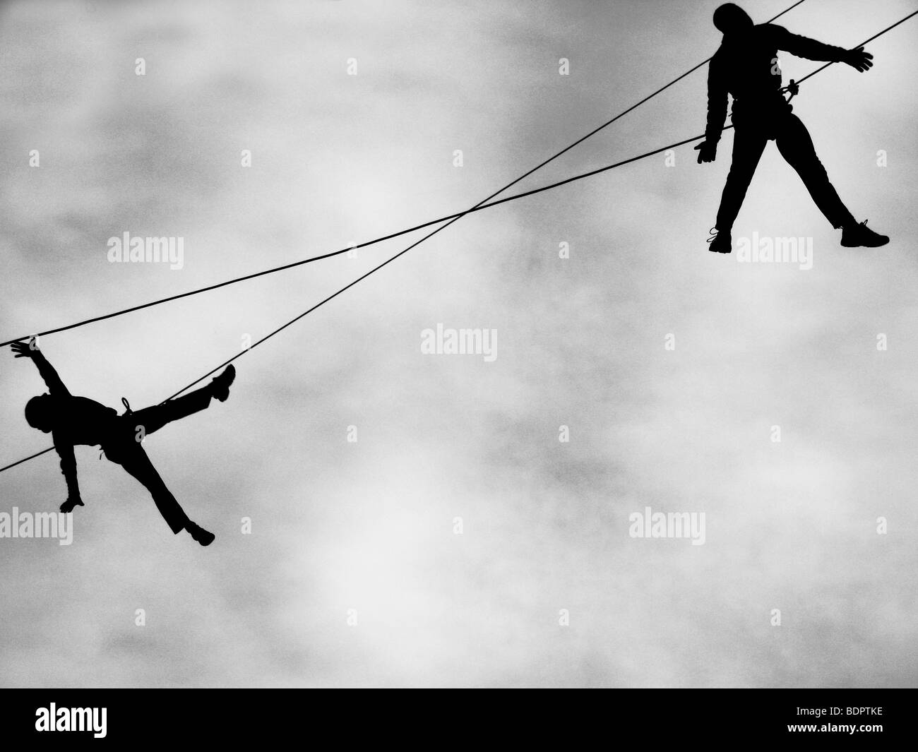 Two figures suspended from high wires Stock Photo - Alamy