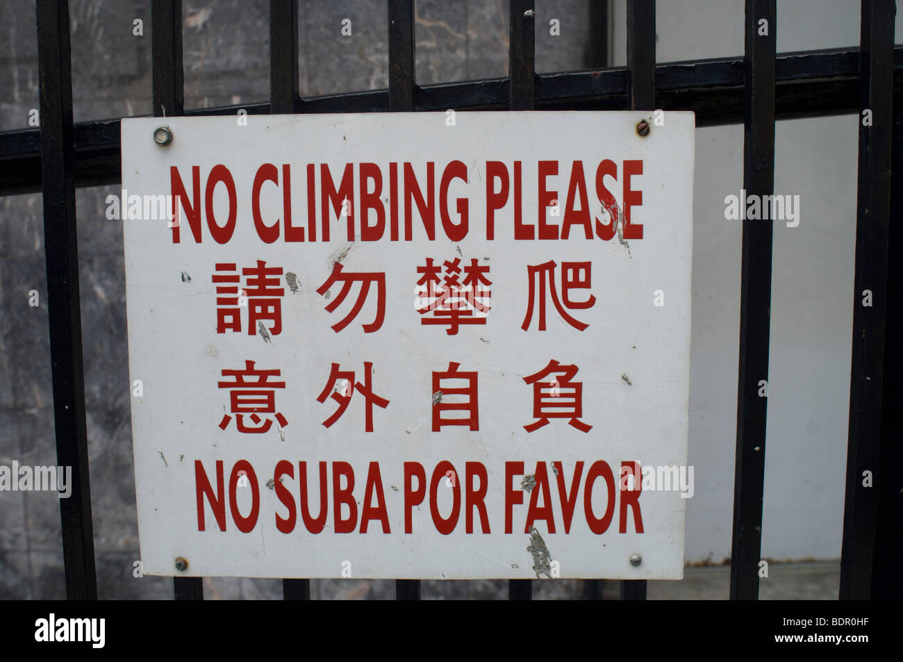 A sign saying no climbing please in English, Chinese and Spanish posted on a fence in Chinatown ...