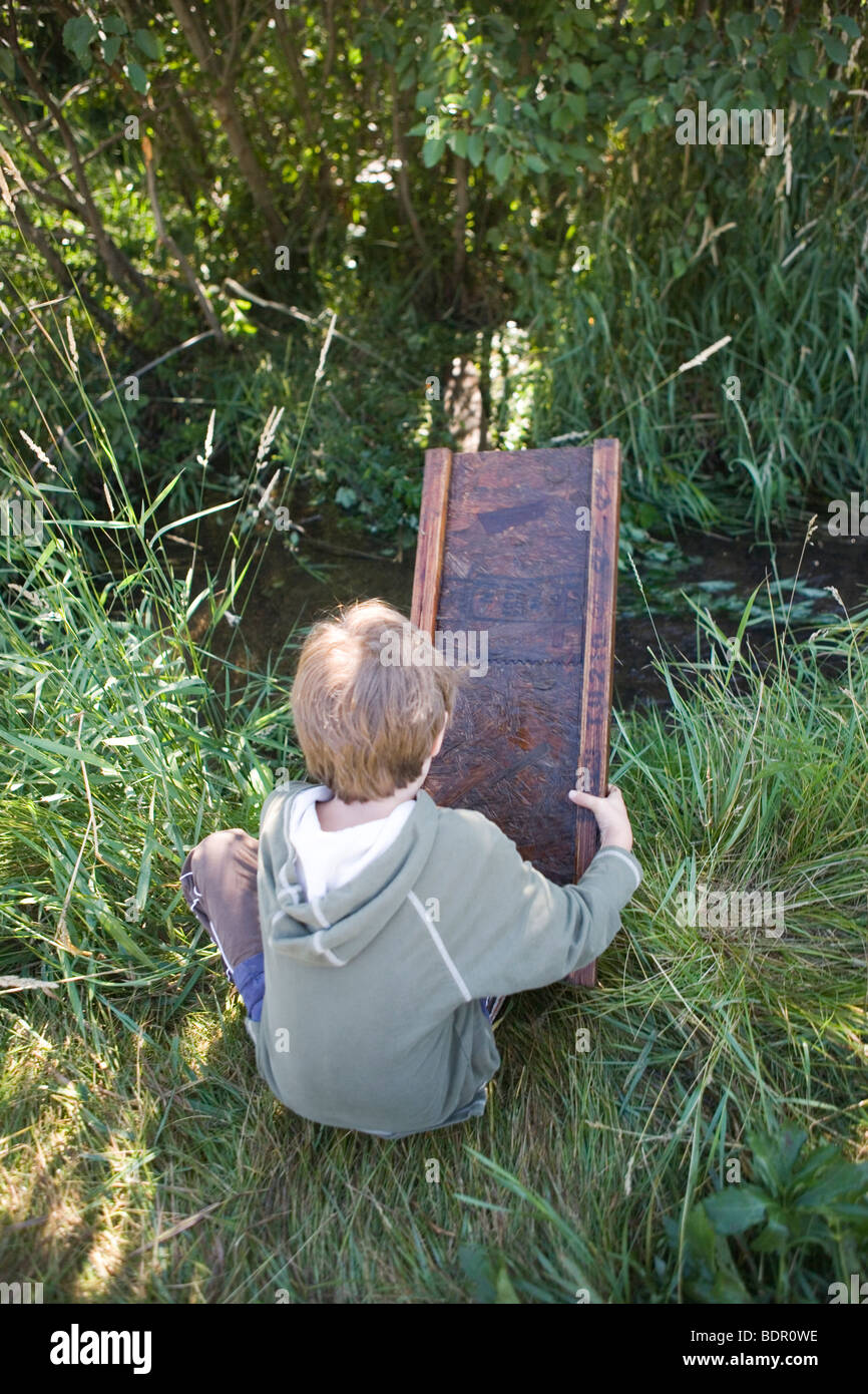 Child building a bridge across a stream using planks of wood Stock ...