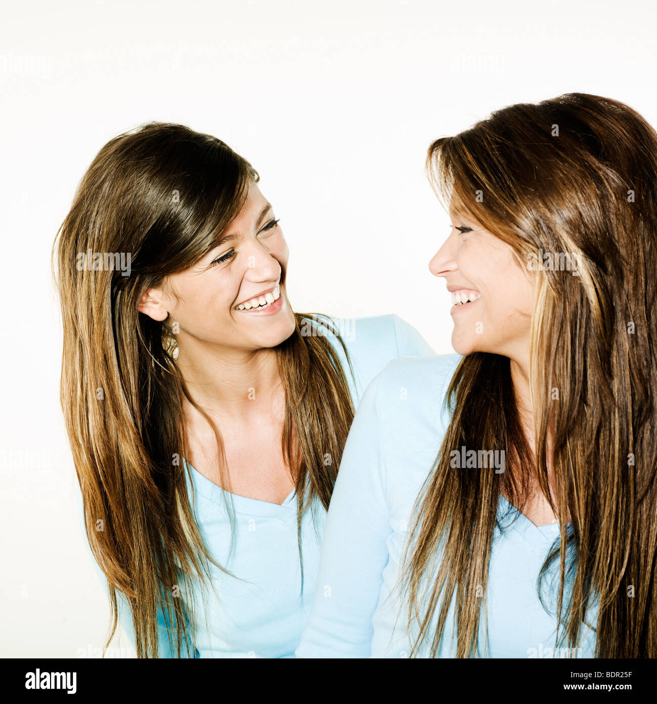 studio shot portrait on isolated background of two sisters twins women ...