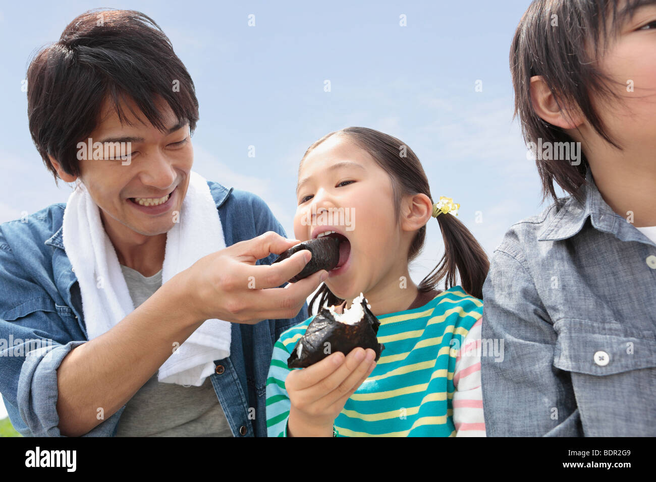 Father and children eating rice ball Stock Photo - Alamy