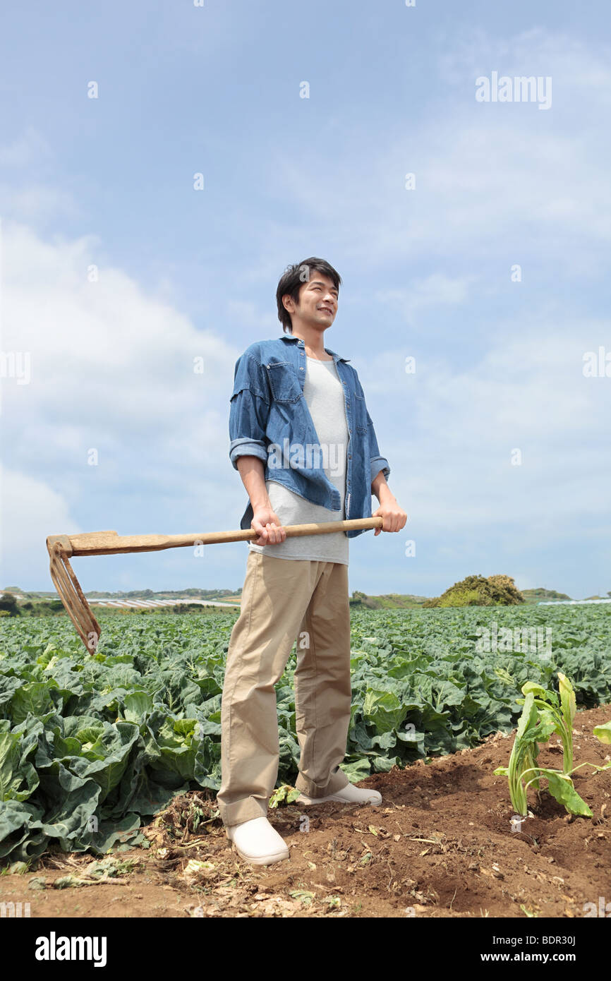 Mid adult man standing with hoe Stock Photo - Alamy