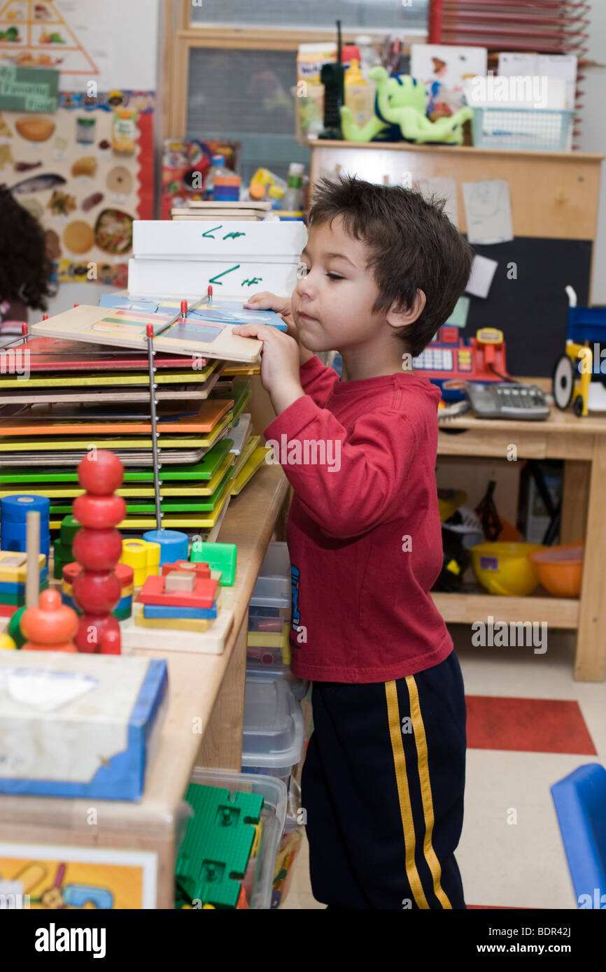 4 year old preschool boy removing a puzzle from the shelf Stock Photo ...
