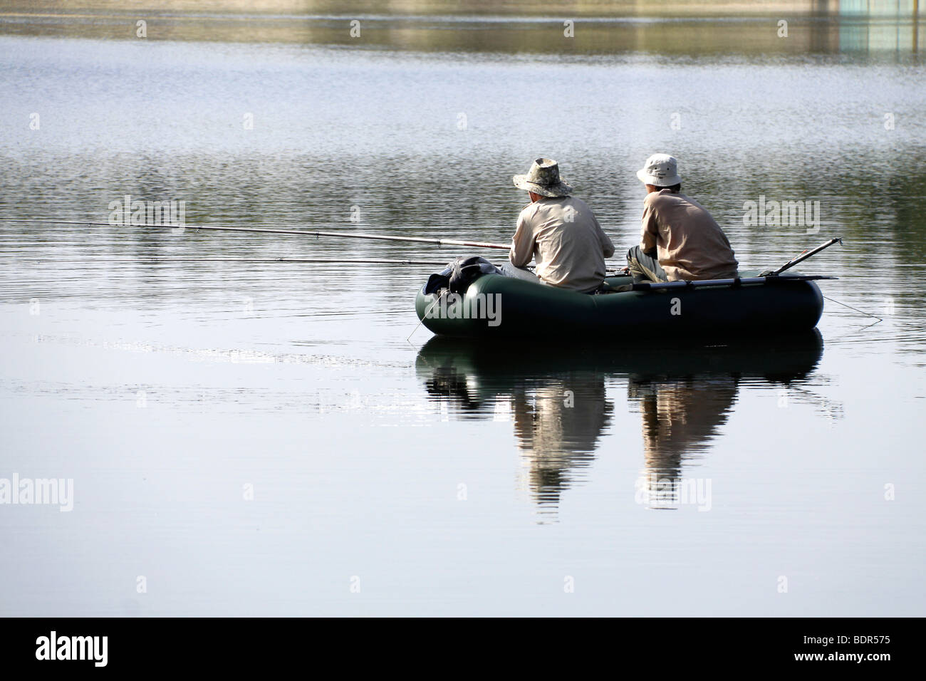 Two fishermen in hats, on an inflatable boat, to cast the line Stock ...