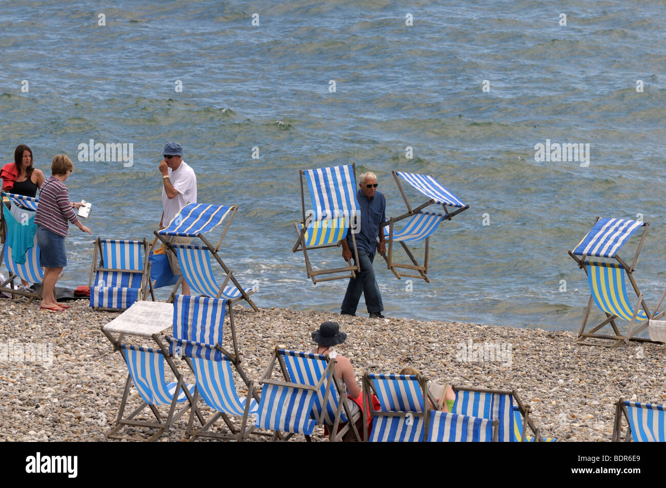 Man carrying two deck chairs on beach at Beer Devon England Stock Photo ...