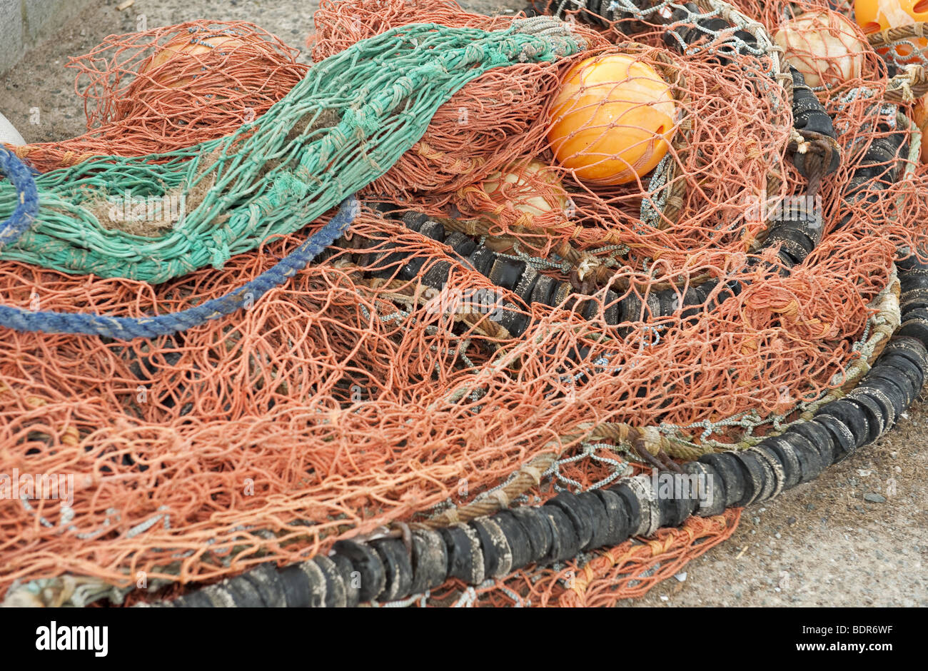 Close up of bright orange sea fishing nets with attached floats piled ...
