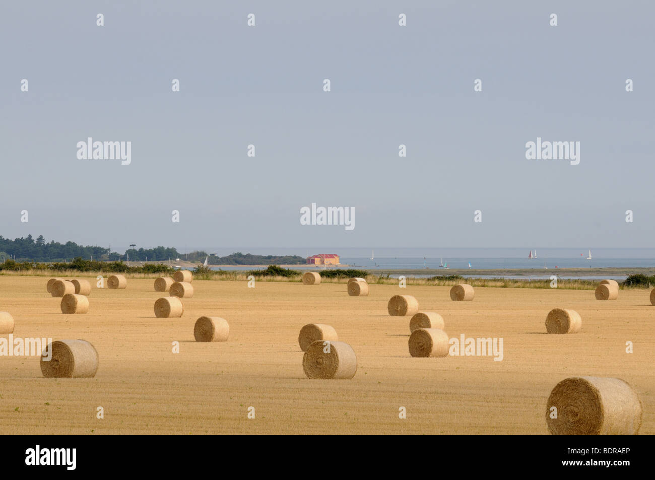 Harvest bales with tidal estuary, lifeboat station and pleasure boats ...