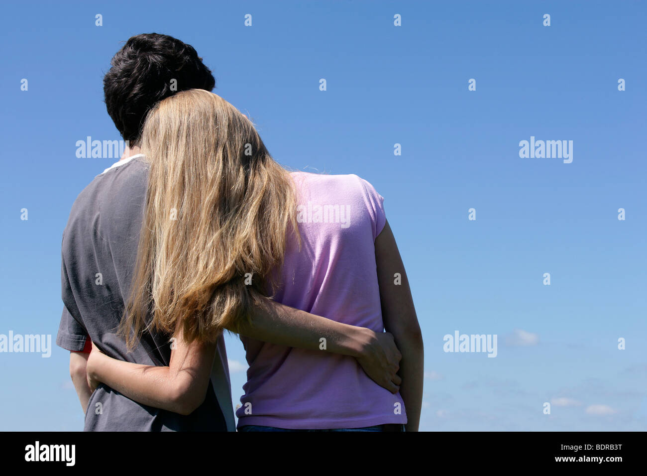 Romantic teenage couple looking at blue sky hugging. Back view Stock ...