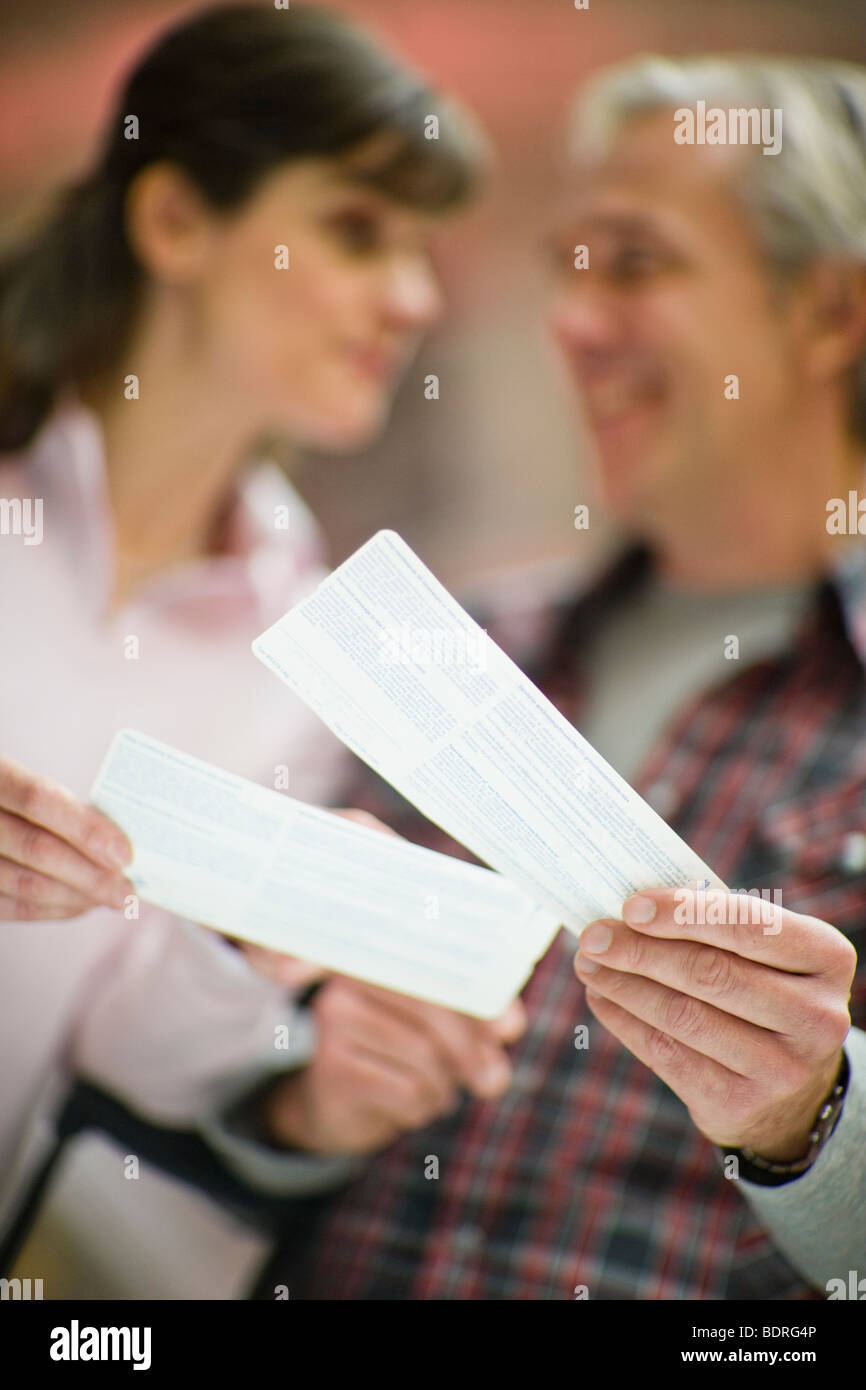 A couple looking at their tickets at a railway station Stock Photo - Alamy