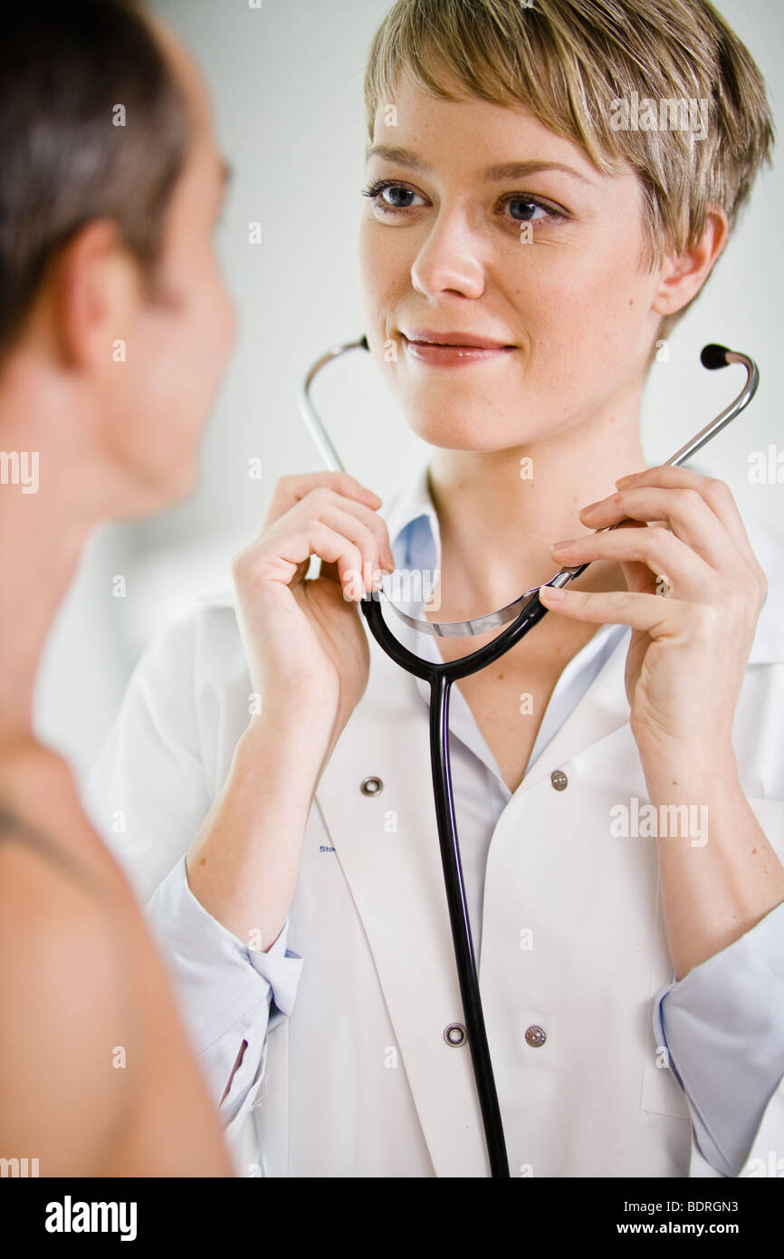 A doctor using a stethoscope at a patient Stock Photo - Alamy