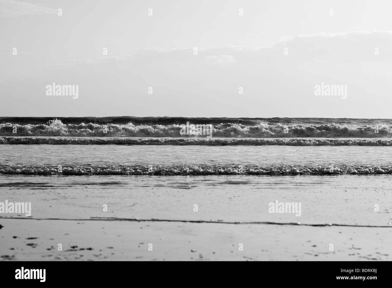 Medium sized waves crash on a beach during sunset Stock Photo - Alamy