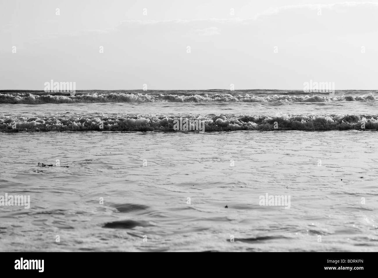 Medium sized waves crash on a beach during sunset Stock Photo - Alamy