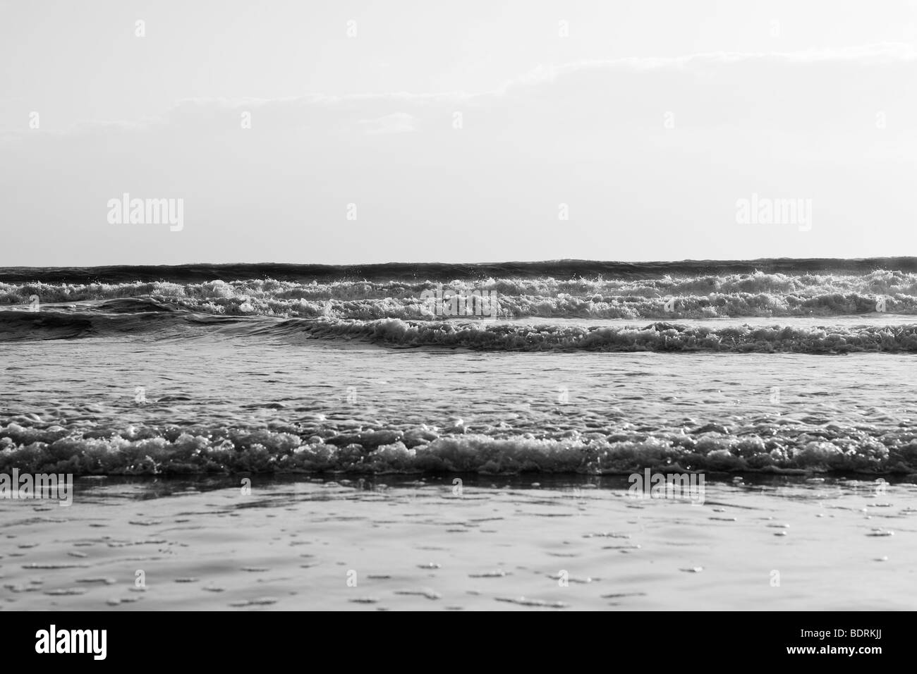 Medium sized waves crash on a beach during sunset Stock Photo - Alamy