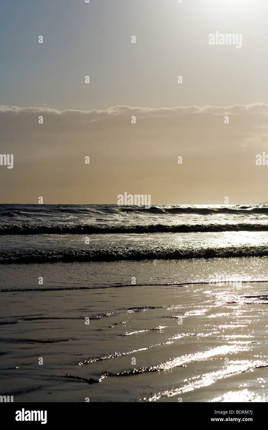 Medium sized waves crash on a beach during sunset Stock Photo - Alamy