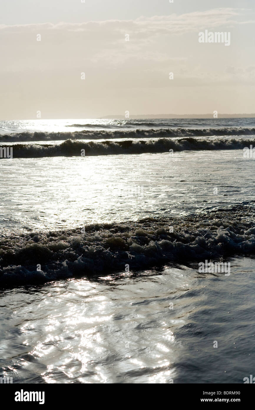 Medium sized waves crash on a beach during sunset Stock Photo - Alamy