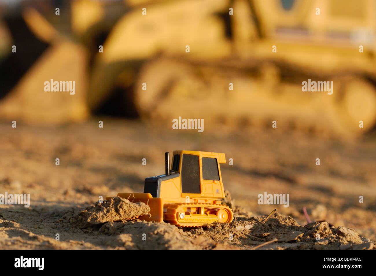 A toy bulldozer sits in front of a real bulldozer Stock Photo - Alamy