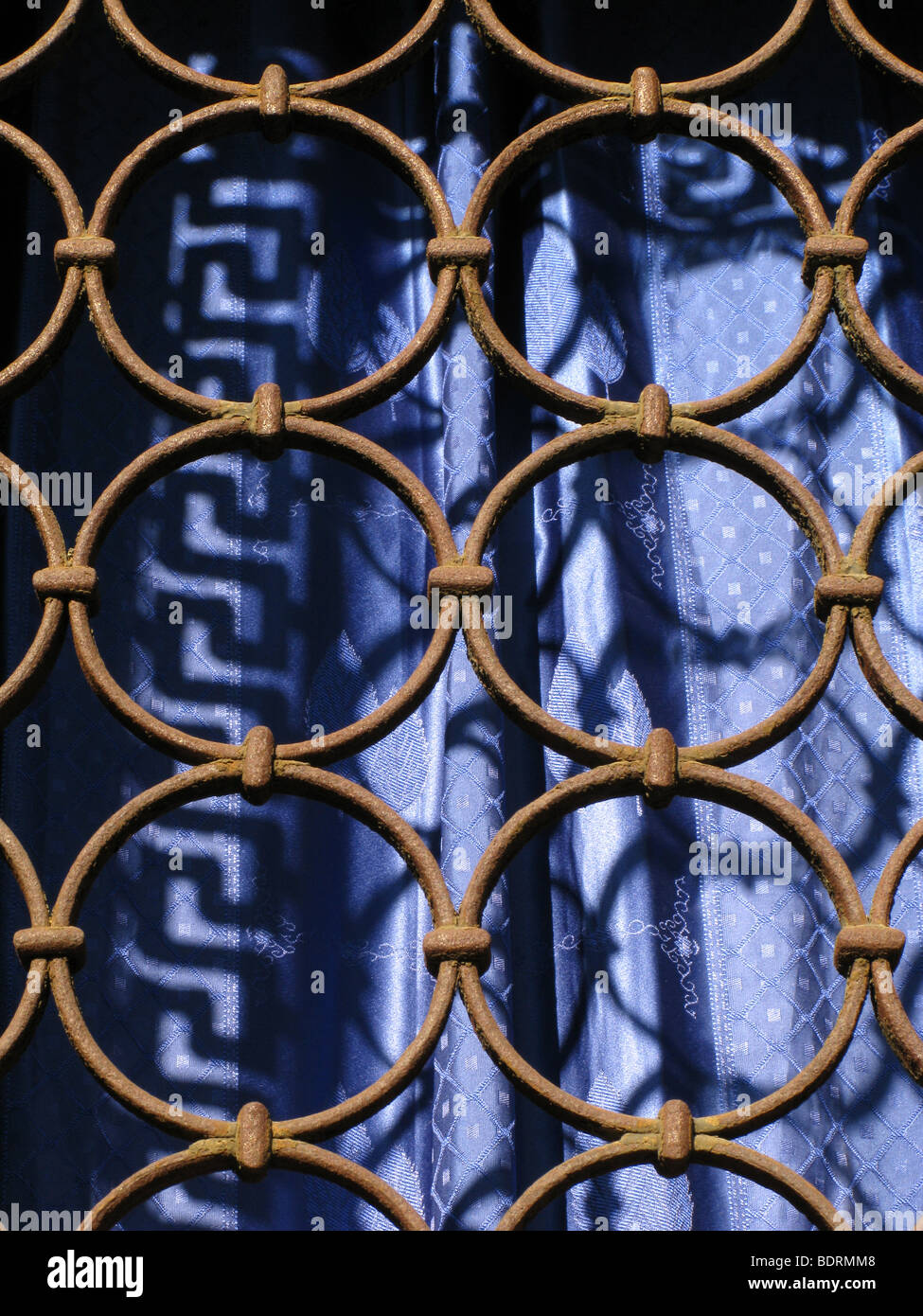 detail of blue curtains on window with rusted metal grill Stock Photo ...