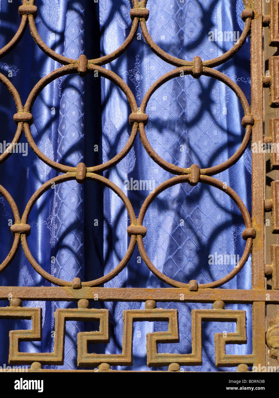 detail of blue curtains on window with rusted metal grill Stock Photo ...