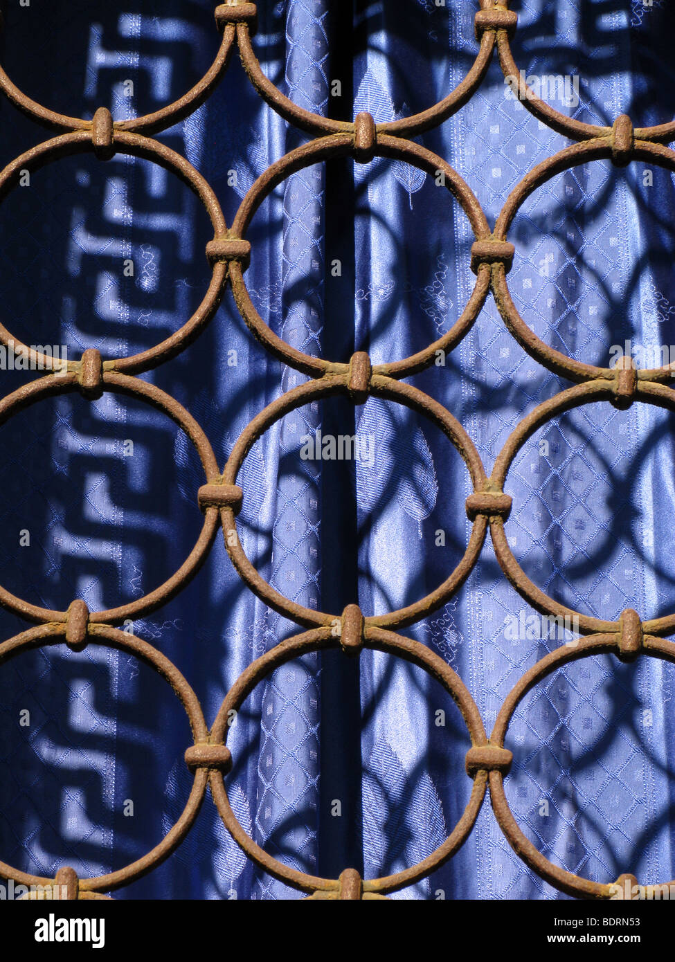 detail of blue curtains on window with rusted metal grill Stock Photo ...