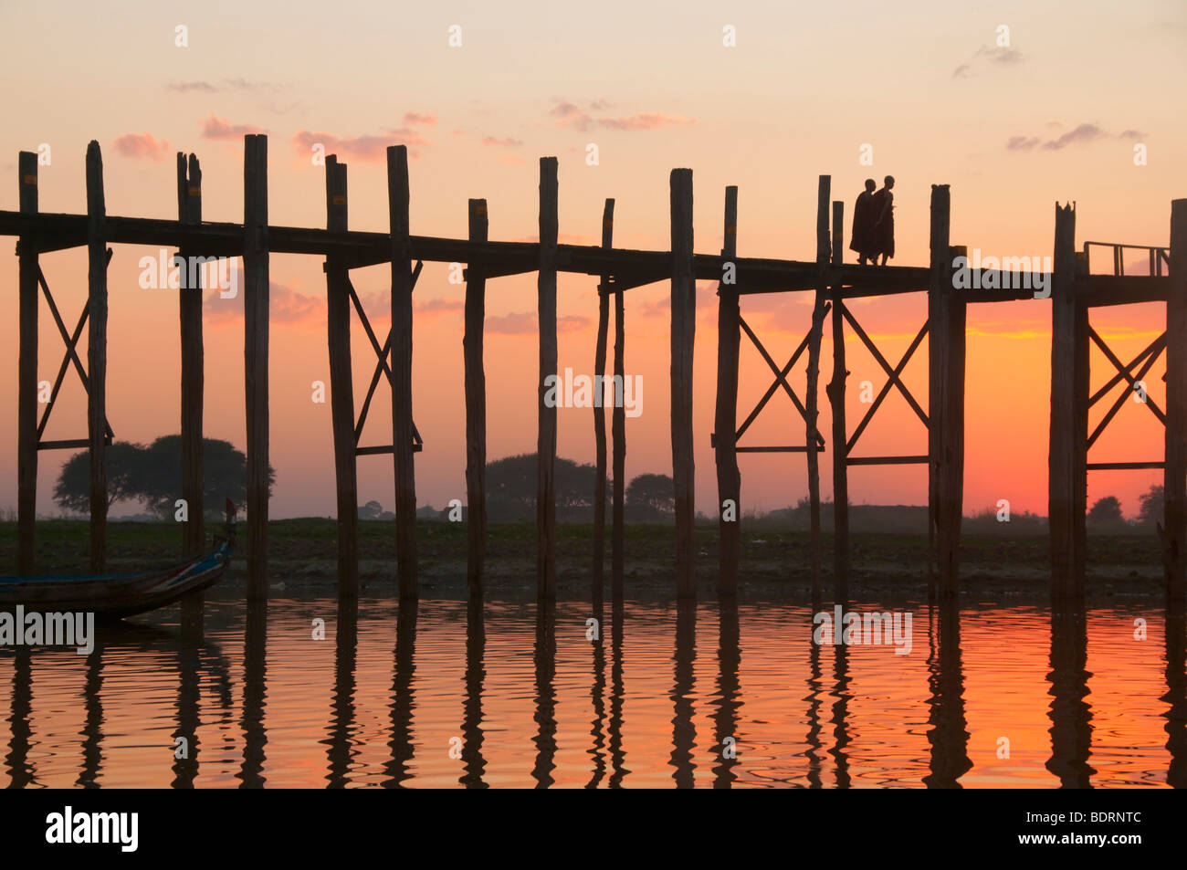 Monks crossing the U Bein Teak Bridge at Sunset in Amarapura near ...