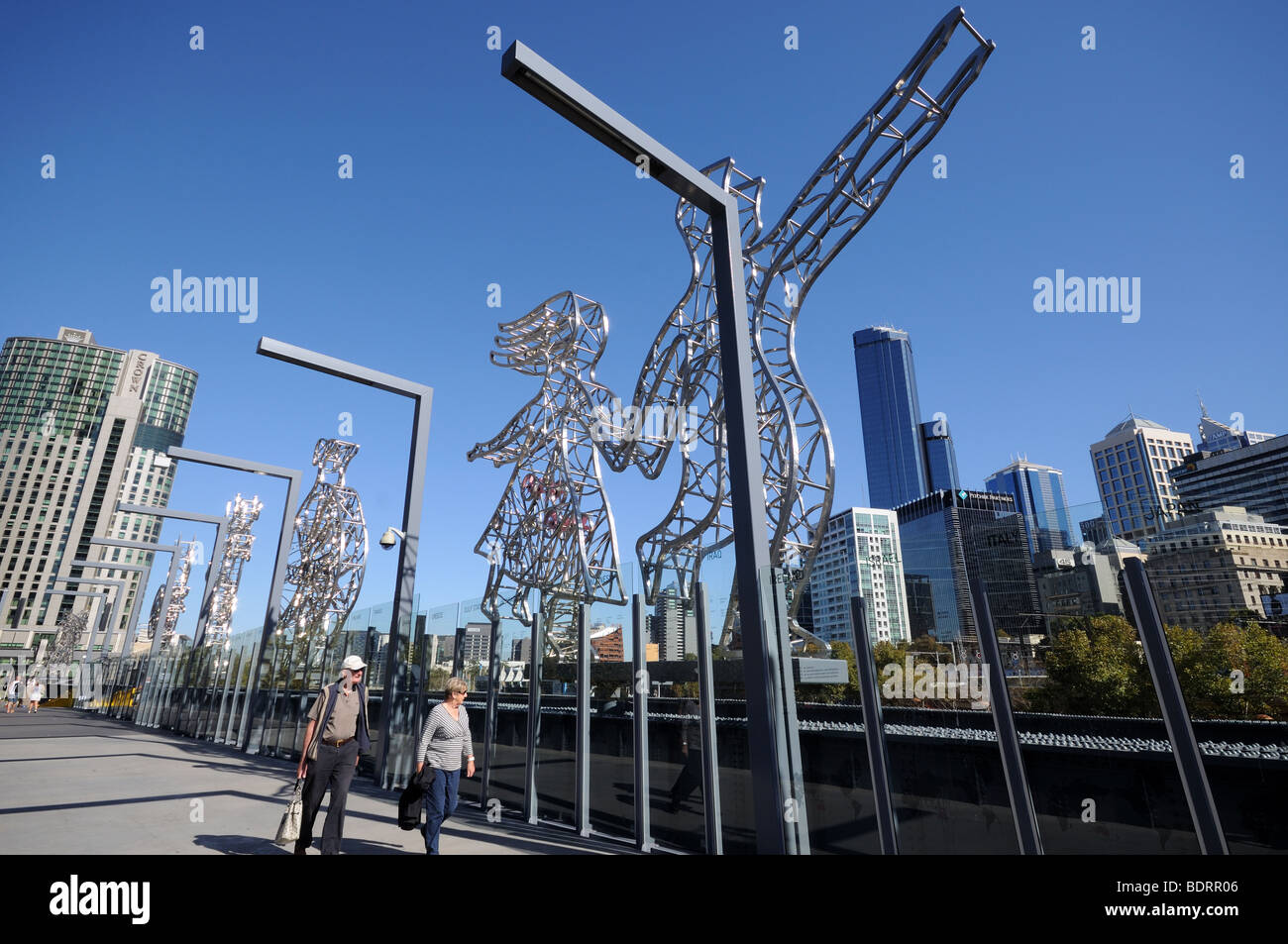 White middle aged couple walking over Sandridge Bridge and sculptures ...