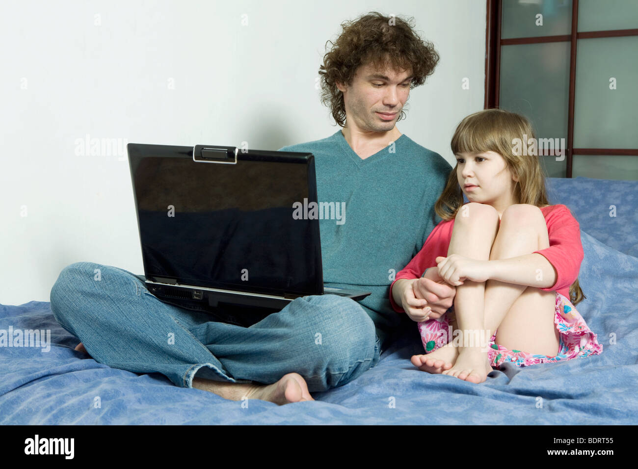 Father working on laptop from home while babysitting his daughter Stock ...