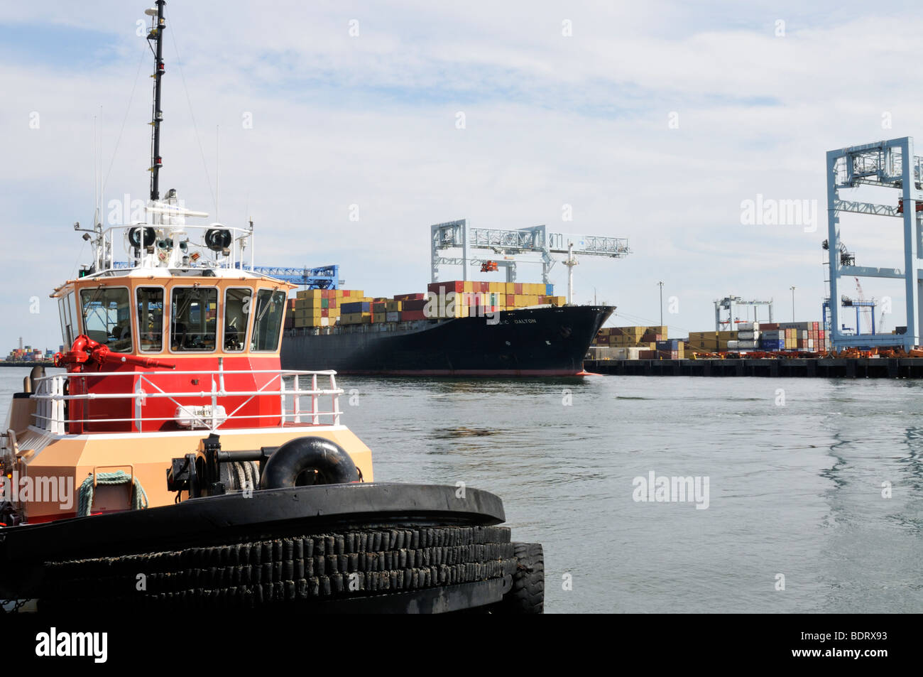 Boston Harbor waterfront with tugboat and container ship at terminal in ...
