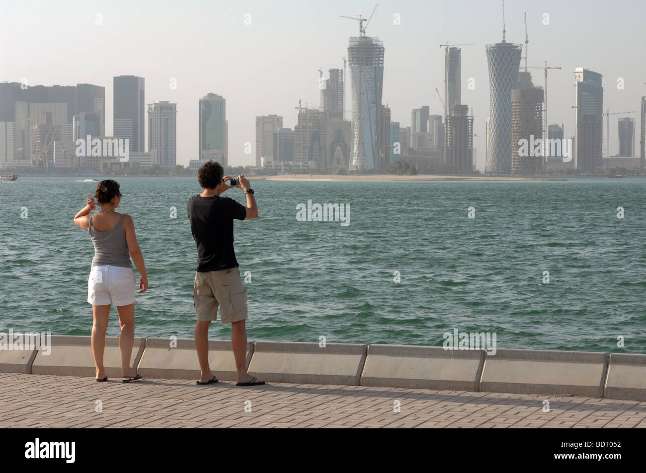Young couple photographing the city skyline of Doha in Qatar from The ...