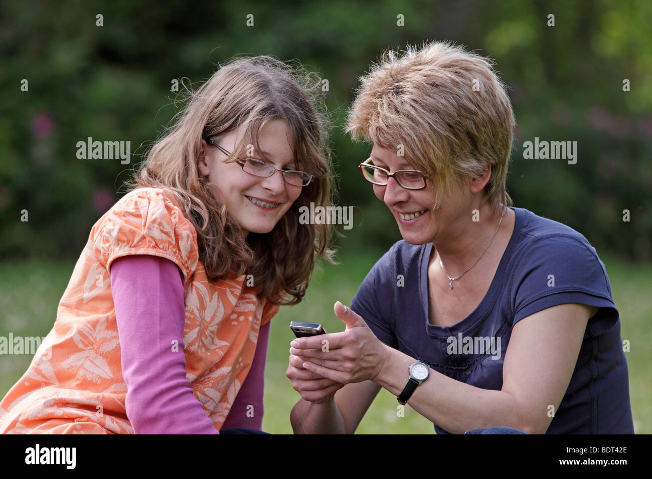 a mother getting her mobile phone explained by her young daughter Stock ...