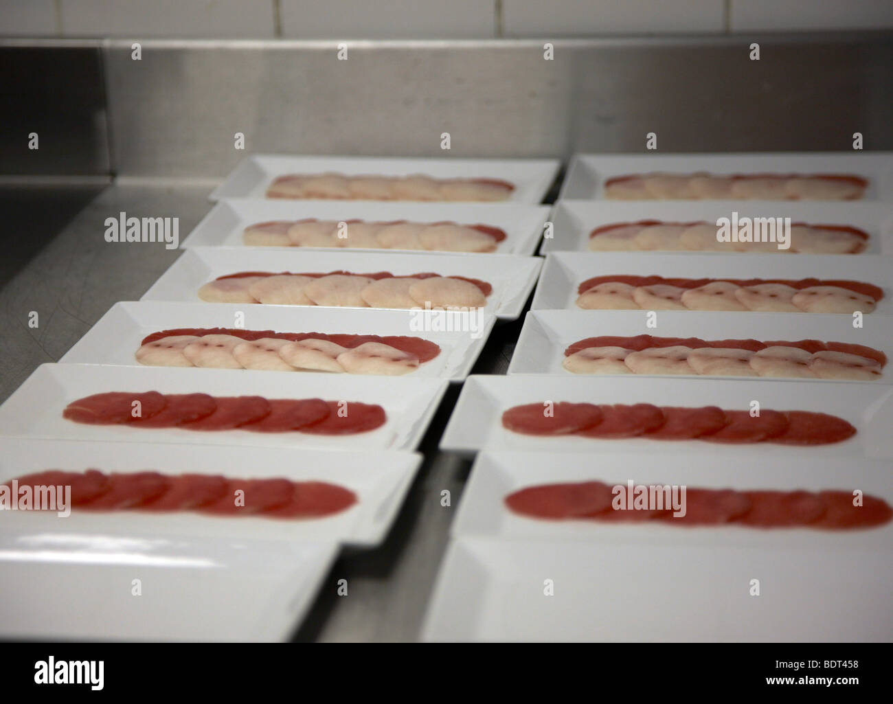 sliced meat layered on plates lined up for service at Maze restaurant ...