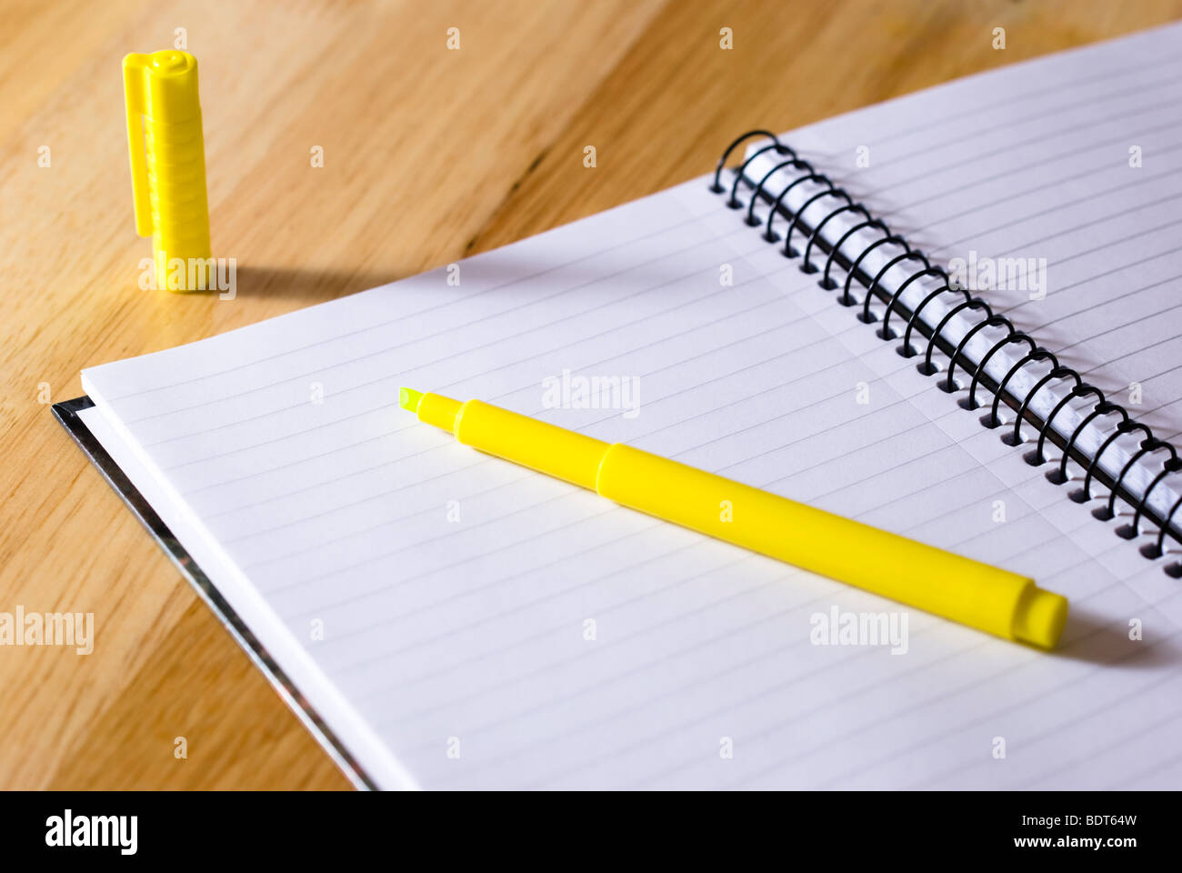 Spiral notebook with yellow highlighter arranged on wooden background ...