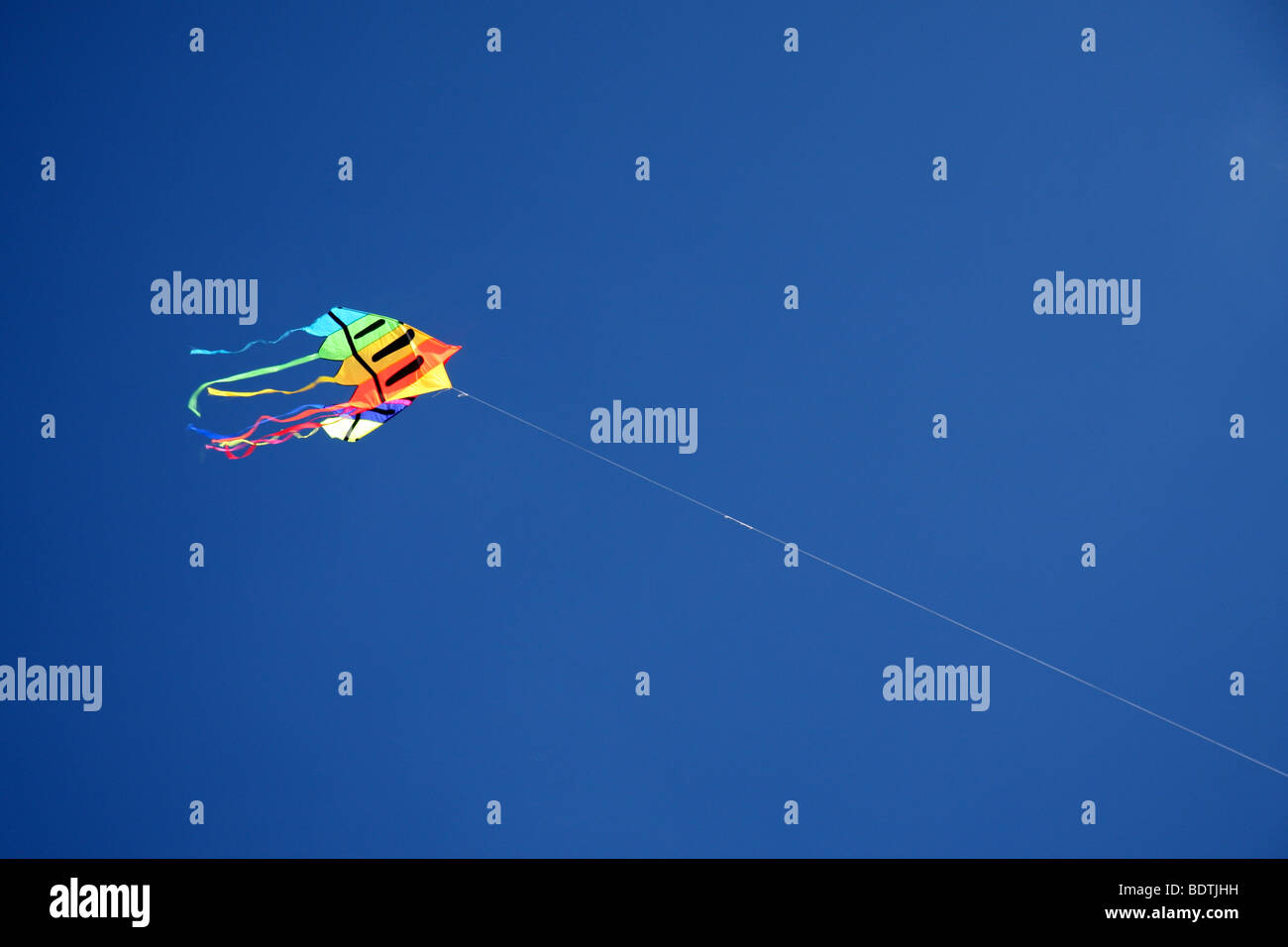 Colourful kite flying in blue sky Stock Photo - Alamy
