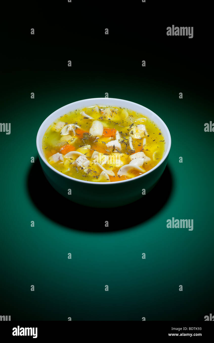 Bowl of soup on dark green table top with very dark shadow around the ...