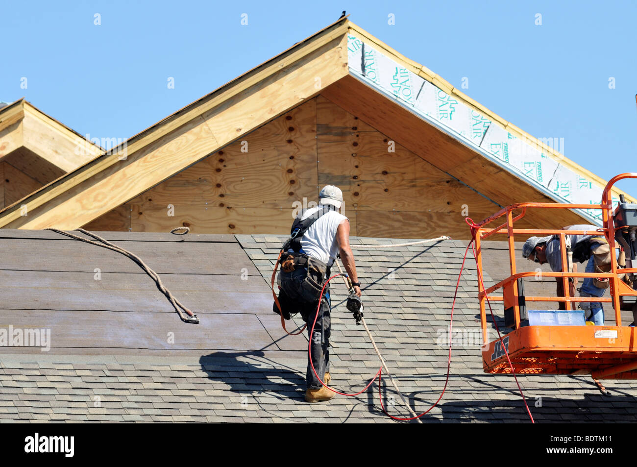 Roofers laying shingles on new building with safety ropes Stock Photo ...