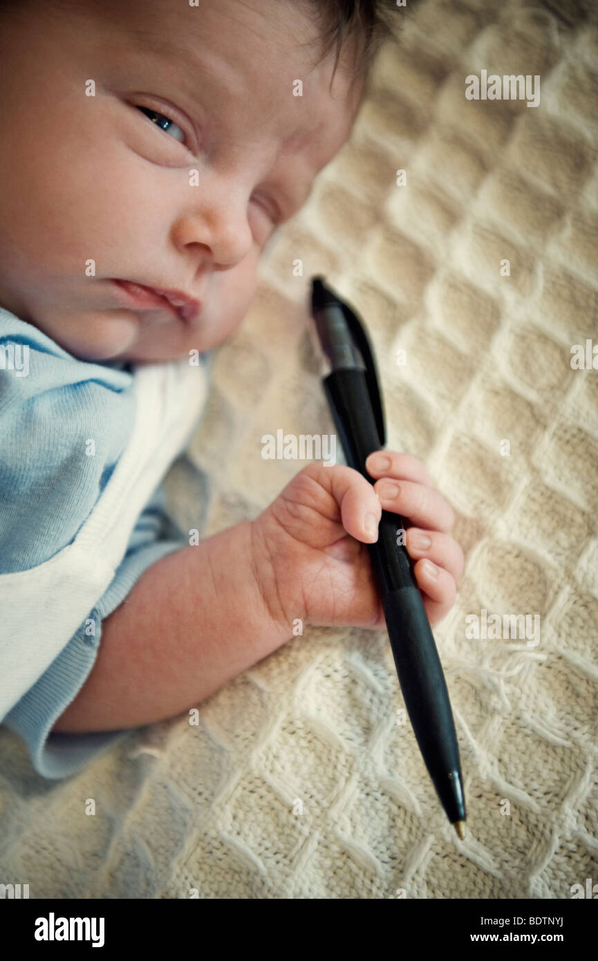 Newborn child holding a pen Stock Photo - Alamy