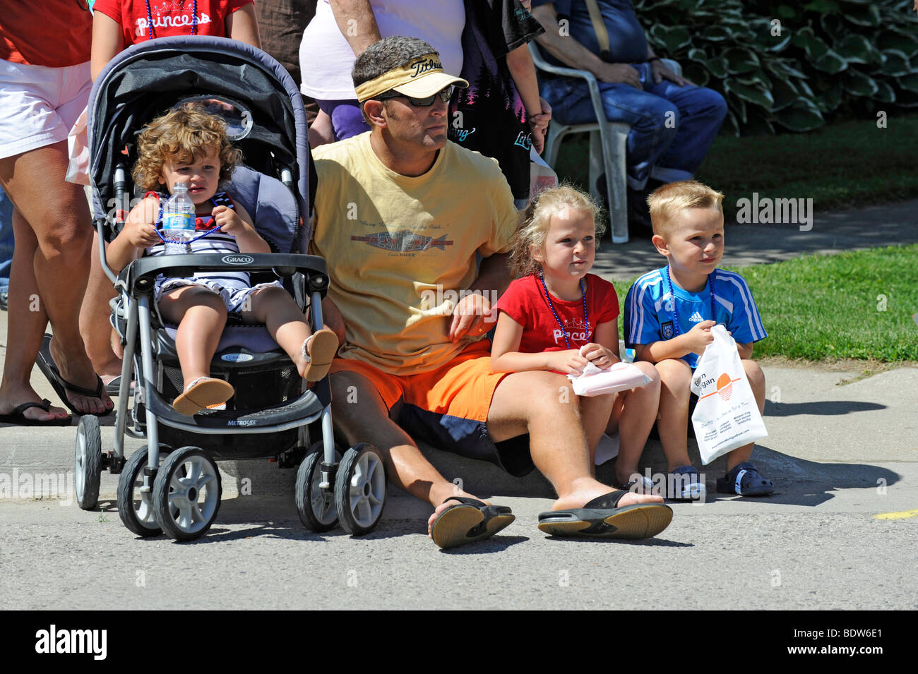 Family watches small town parade Stock Photo - Alamy