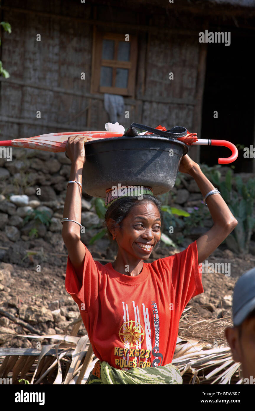 TIMOR LESTE Woman carrying plastic bowl and umbrella, Kefua village ...